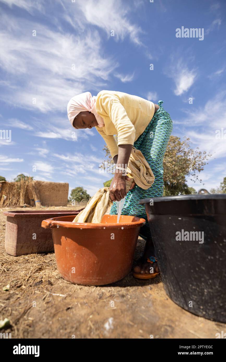An IDP girl washes clothes with a washing board in Segou Region, Mali ...