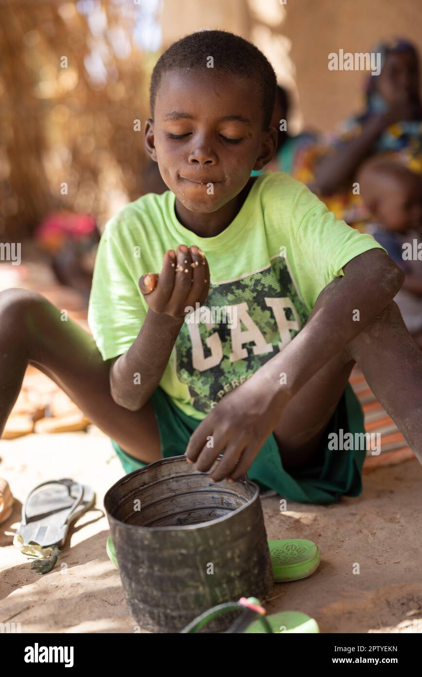 A boy child eats rice out of a communal bowl with his family in Segou ...