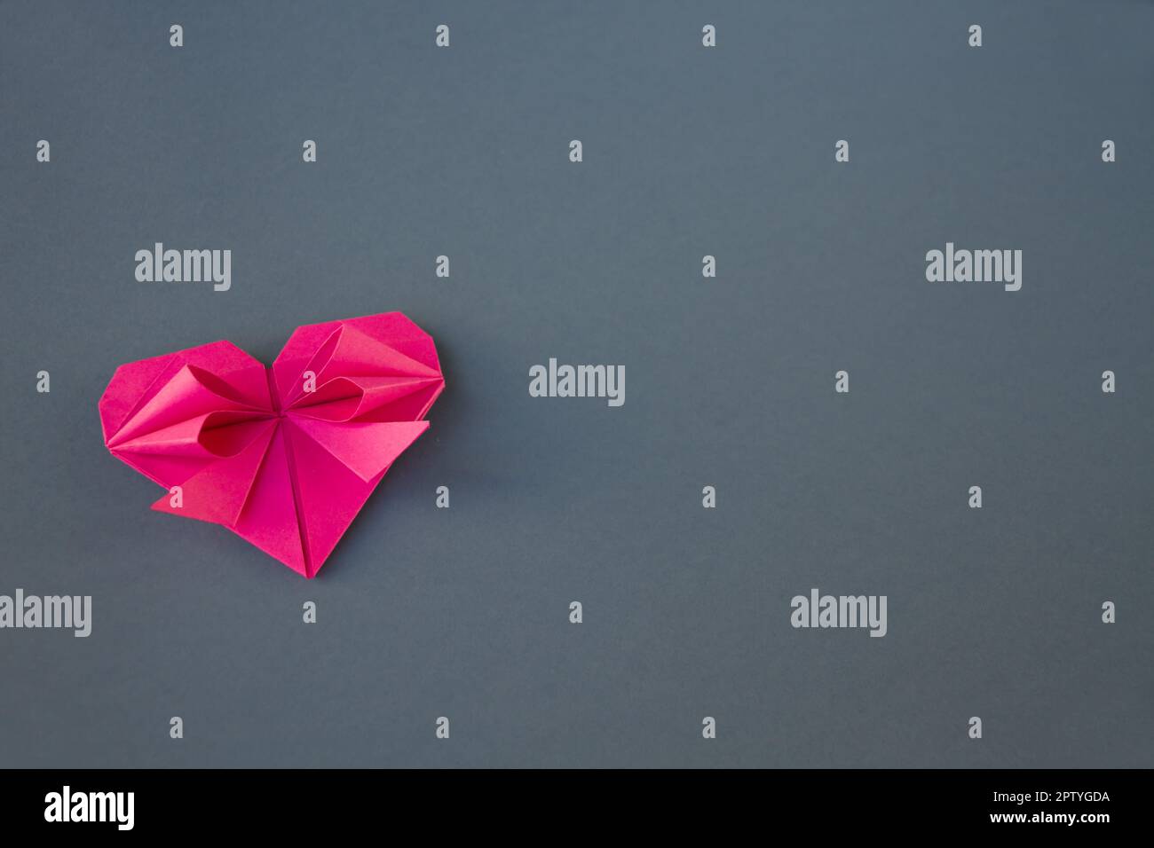 Pink paper heart origami isolated on a blank grey background ...