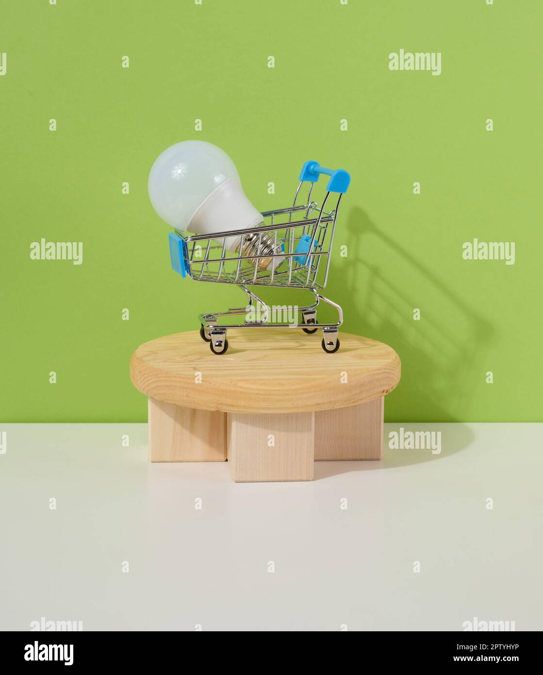 A miniature iron cart and a glass white lamp on a green background ...