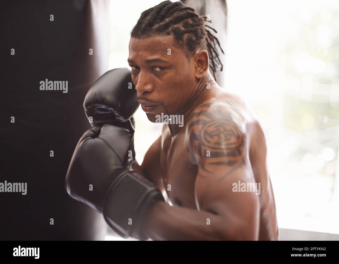 Take your best shot. Portrait of a young boxer practicing in a gym ...