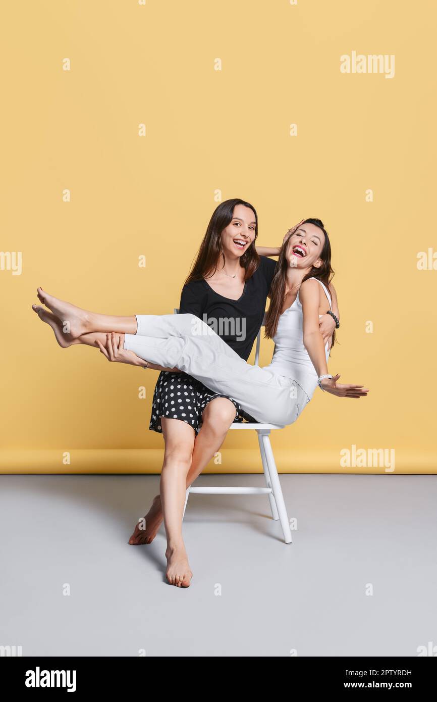 Two happy sisters sit on one chair together Stock Photo - Alamy