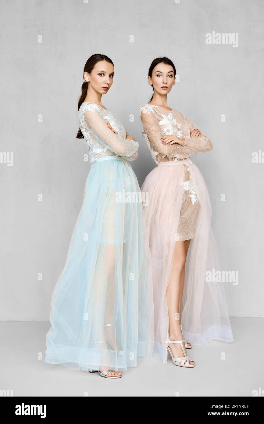 Two beautiful young women in transparent tulle dresses with lace posing ...