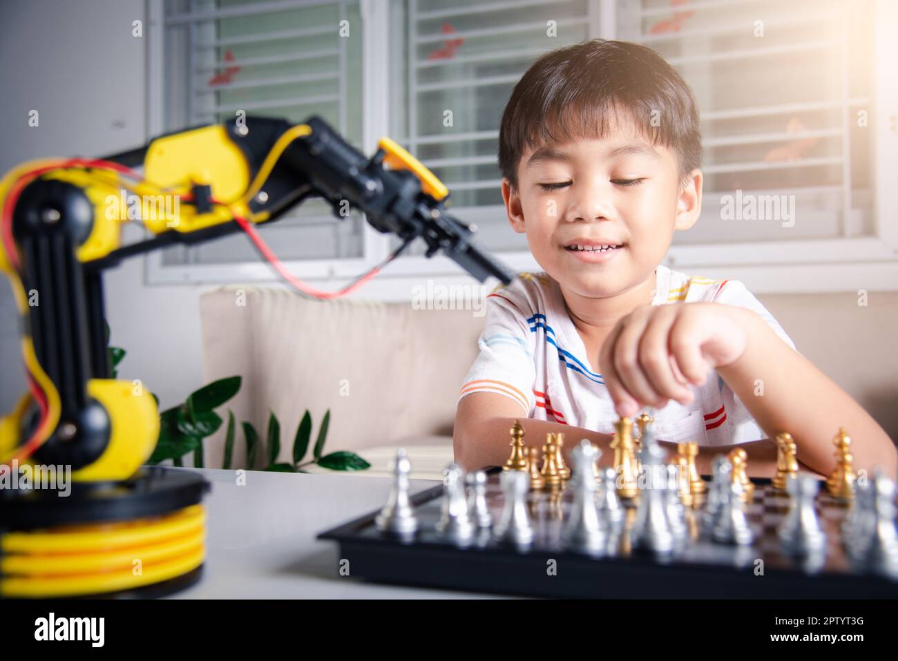 Asian little boy is playing chess with robot machine arm, STEM ...