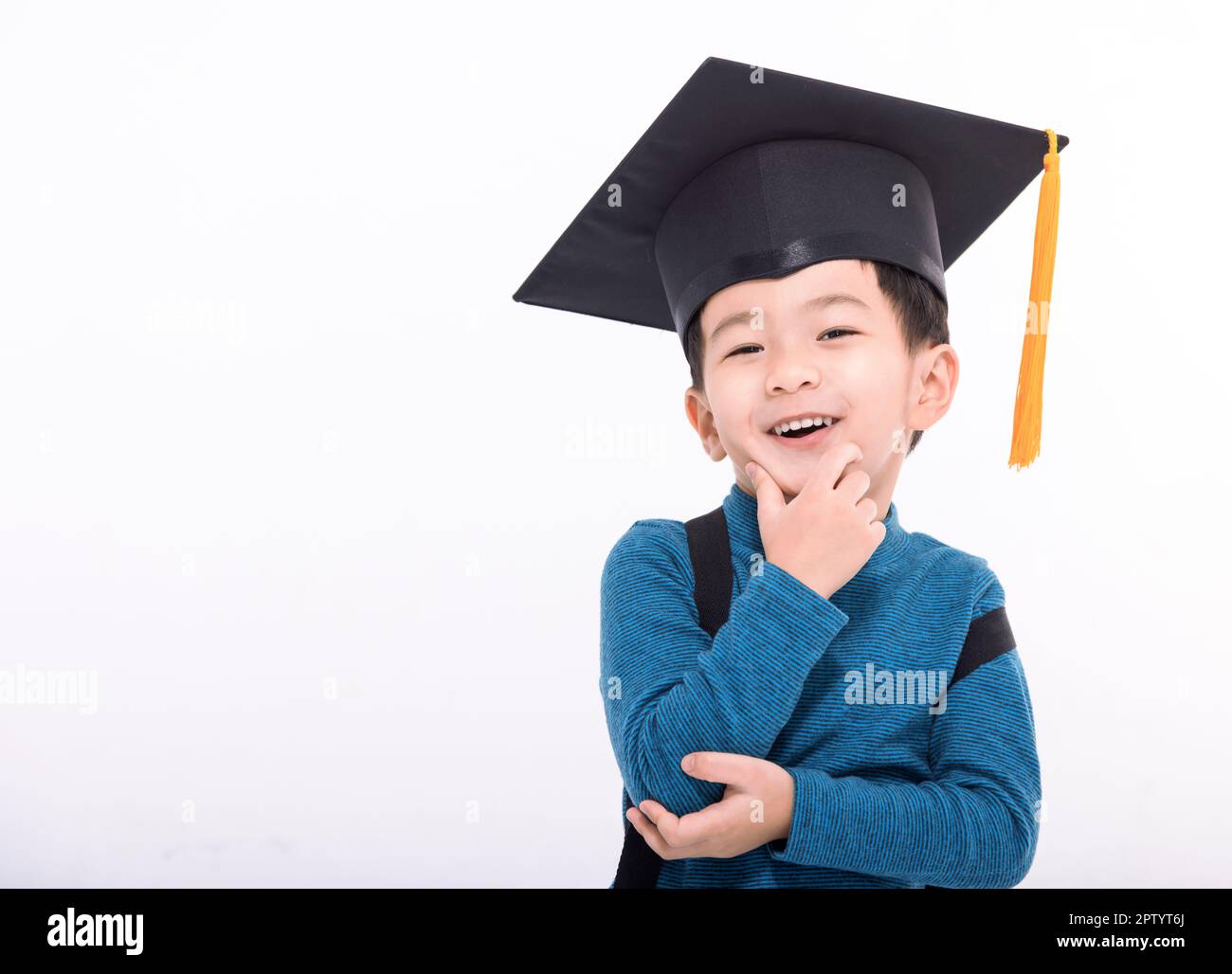 Happy little boy student in a graduate cap thinking and looking at ...