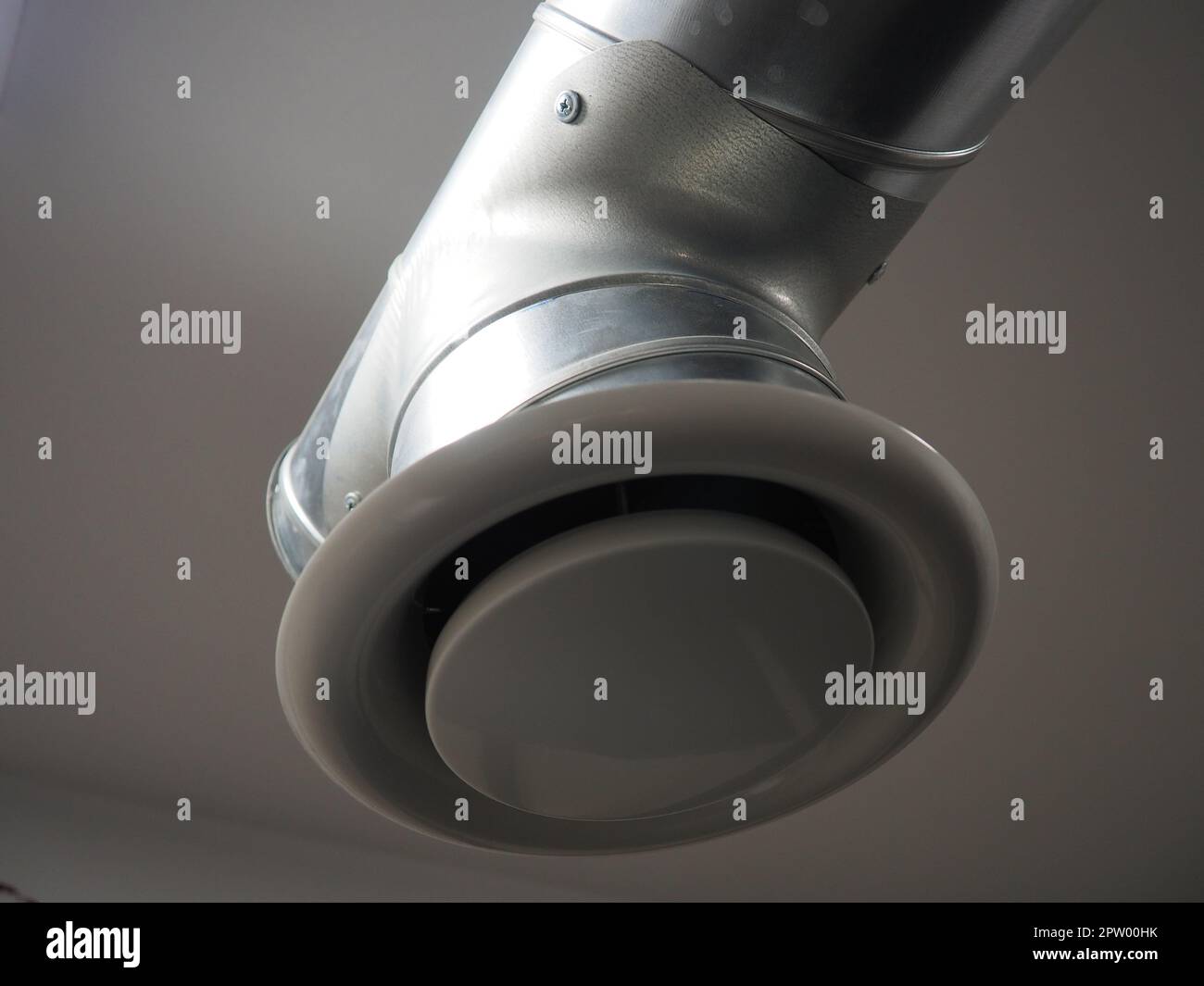 Extractor hood in a public toilet. Round metal pipe with gray air ...