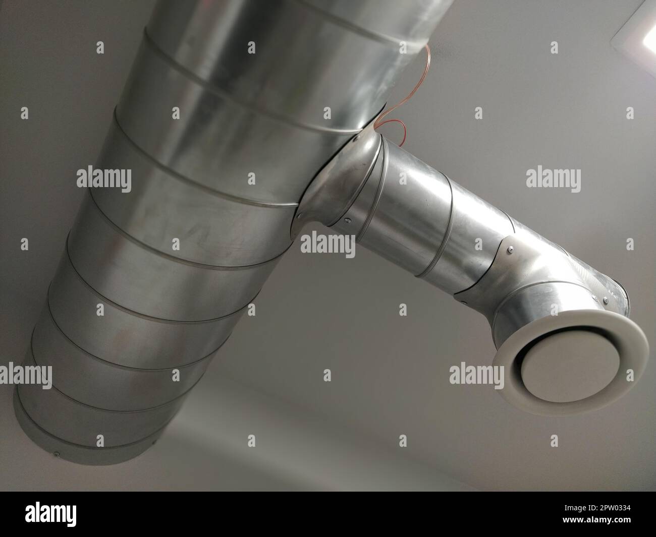 Extractor hood in a public toilet. Round metal pipe with gray air ...