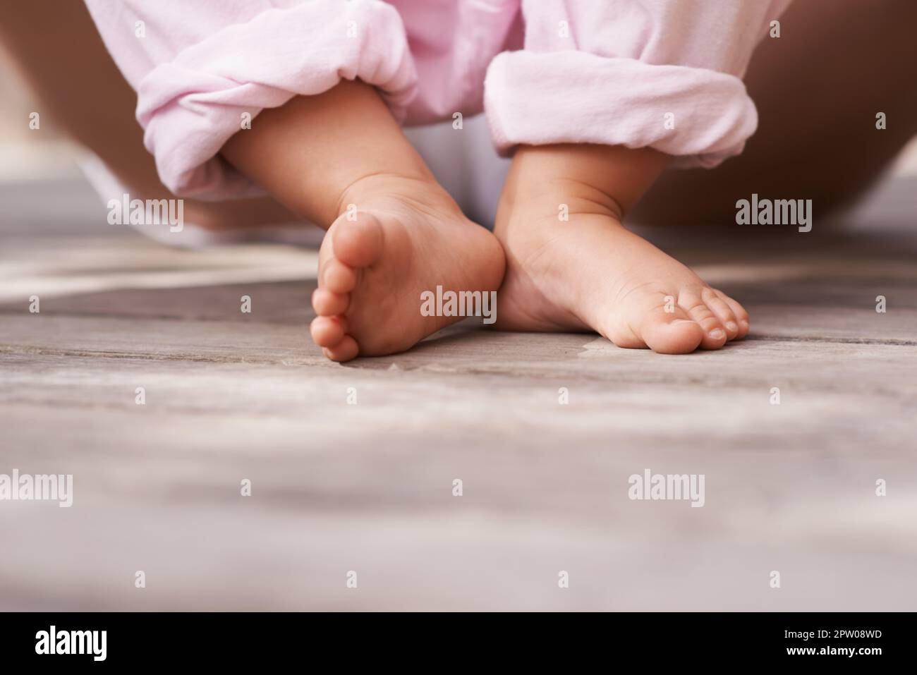 Teeny tiny toes. Closeup image of a babys feet as she sits outside with ...