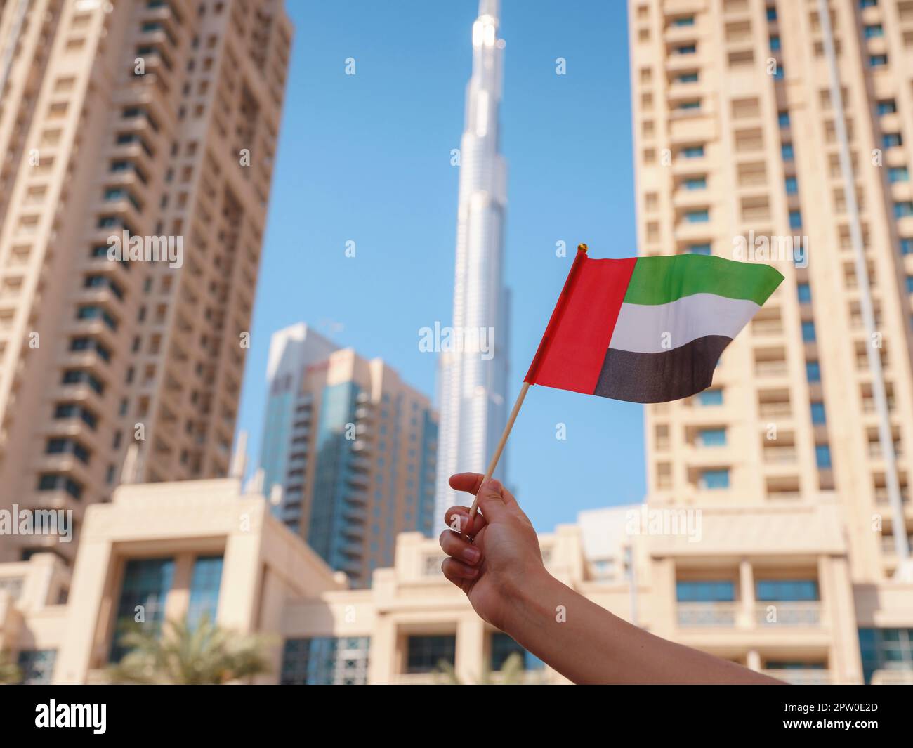 Close up of a female hand holding tiny flag of UAE against Dubai ...
