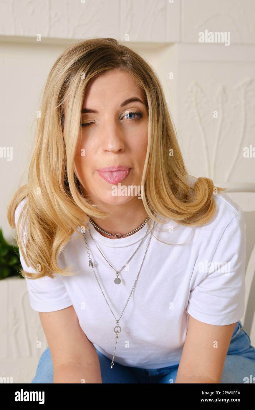 Joyful blonde woman sticking out tongue Stock Photo - Alamy
