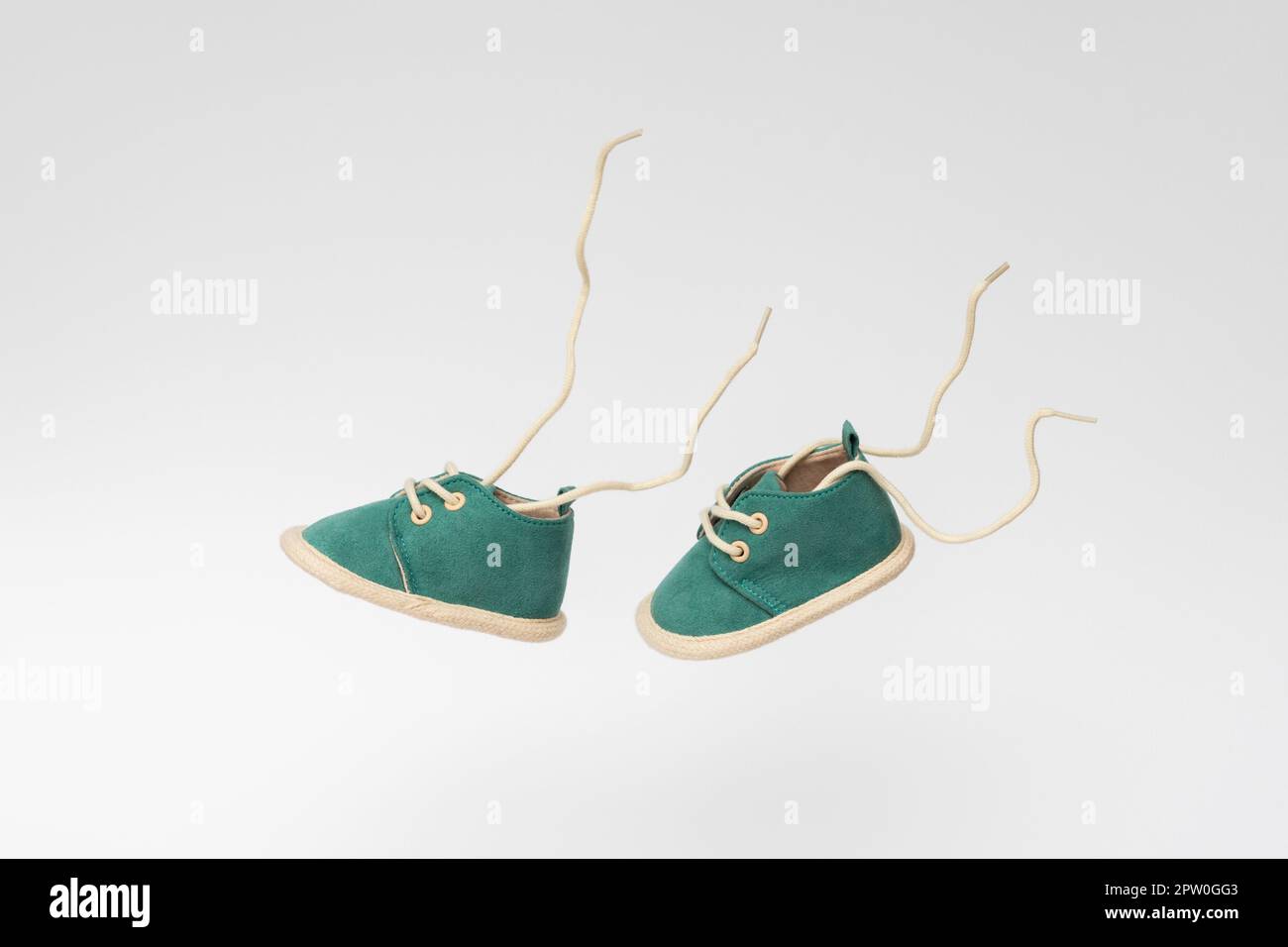 Pair of baby shoes flying in the air simulating walking on a white ...
