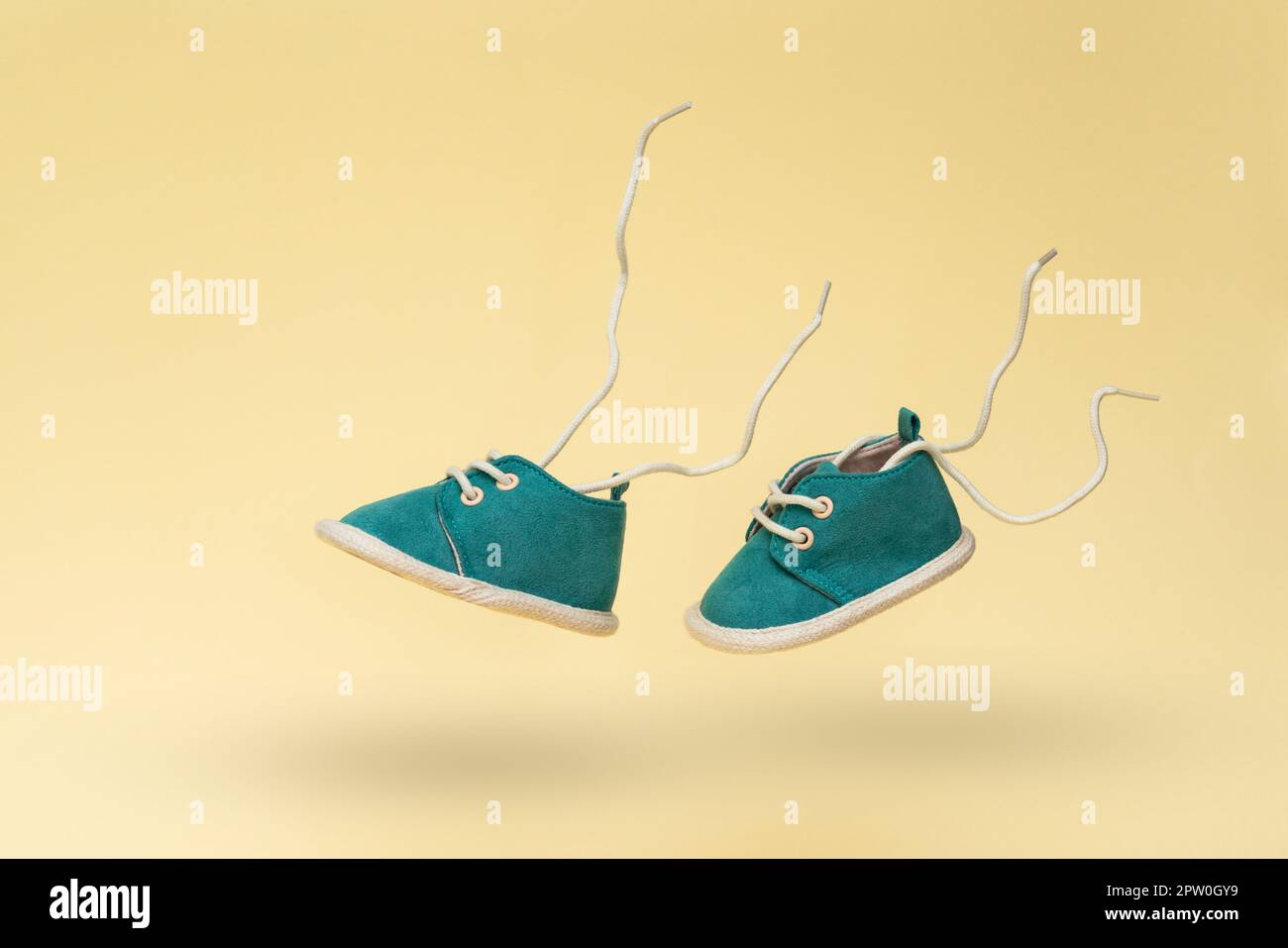 Flying baby shoes with flying laces on yellow background. Newborn baby ...