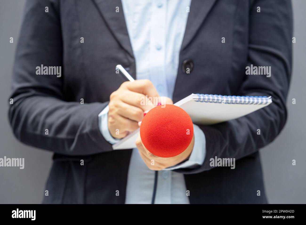 Female reporter at press conference or media event, writing notes ...