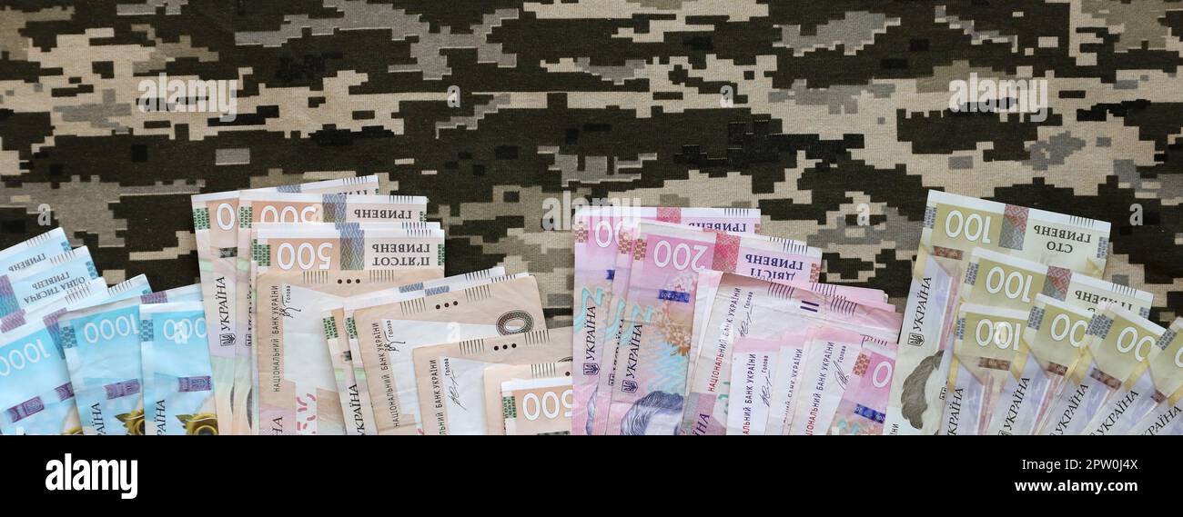 Ukrainian hryvnya bills on fabric with texture of Ukrainian military ...