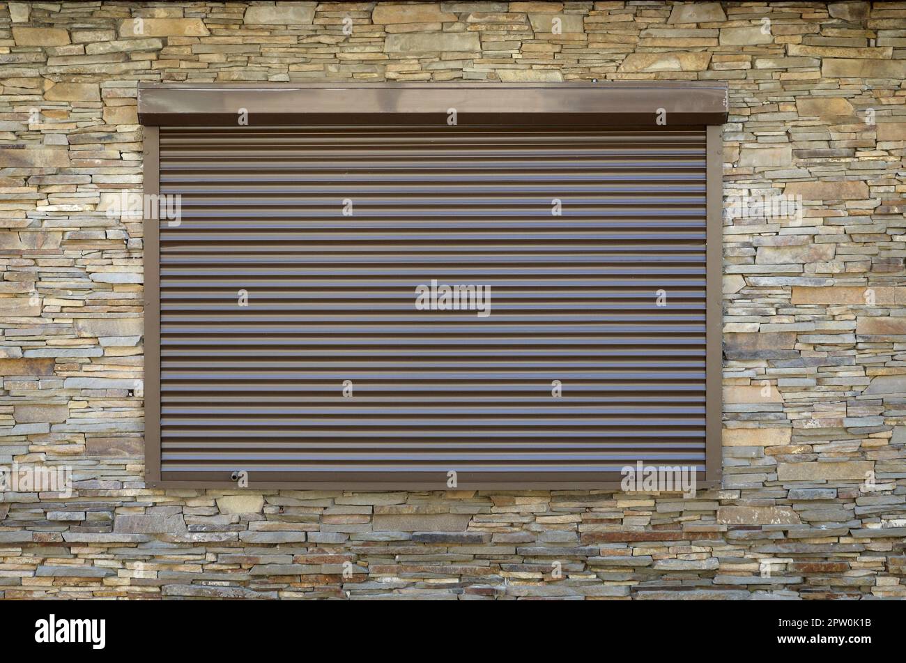 A window with brown metal rolling shutters. Wall decoration with ...