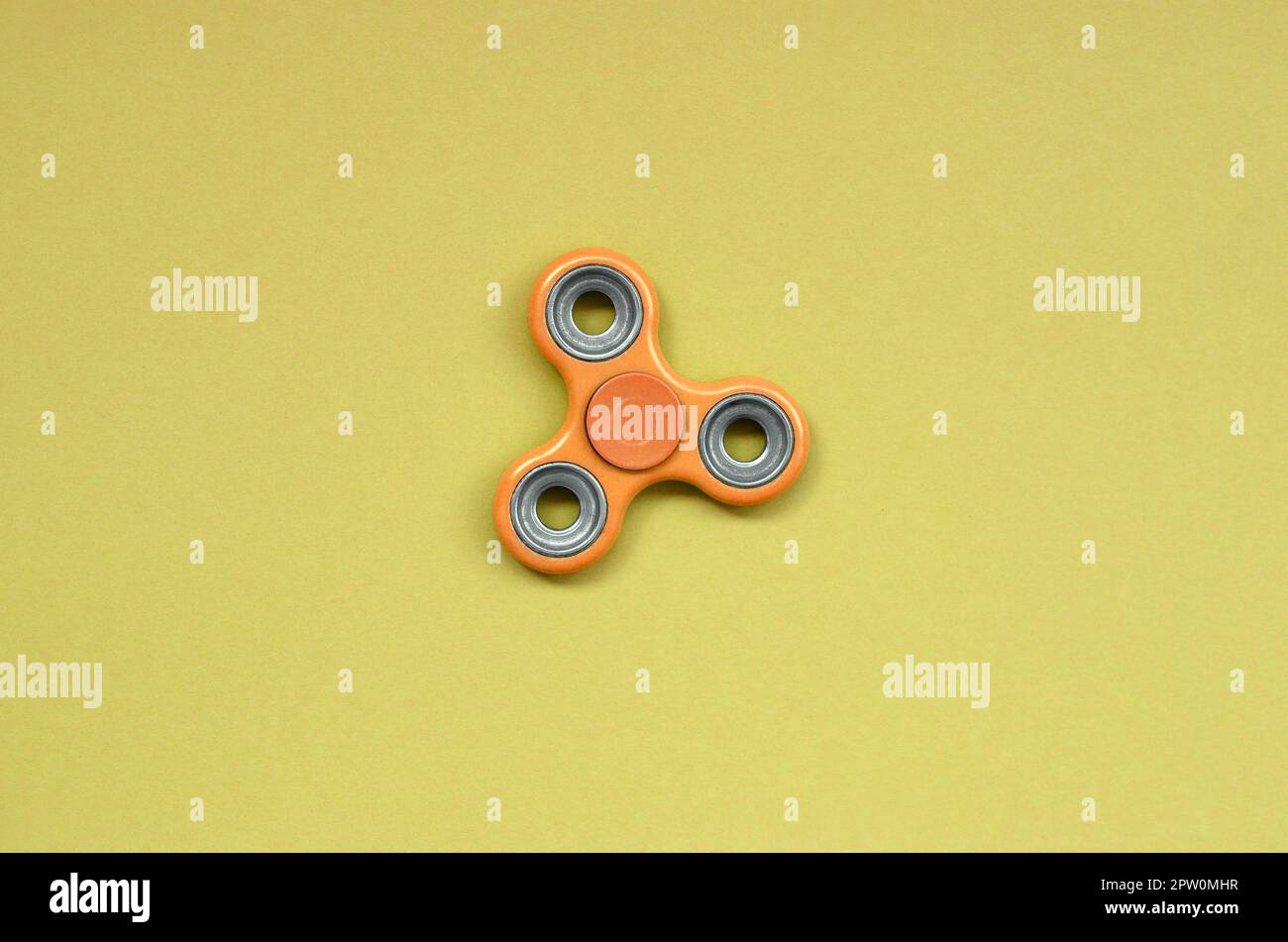 orange fidget spinner lies on texture background of fashion pastel ...