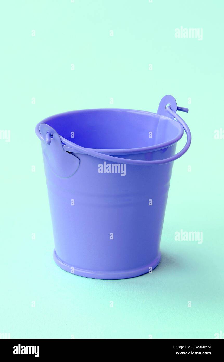 A miniature empty lilac bucket lies on a green pastel background ...