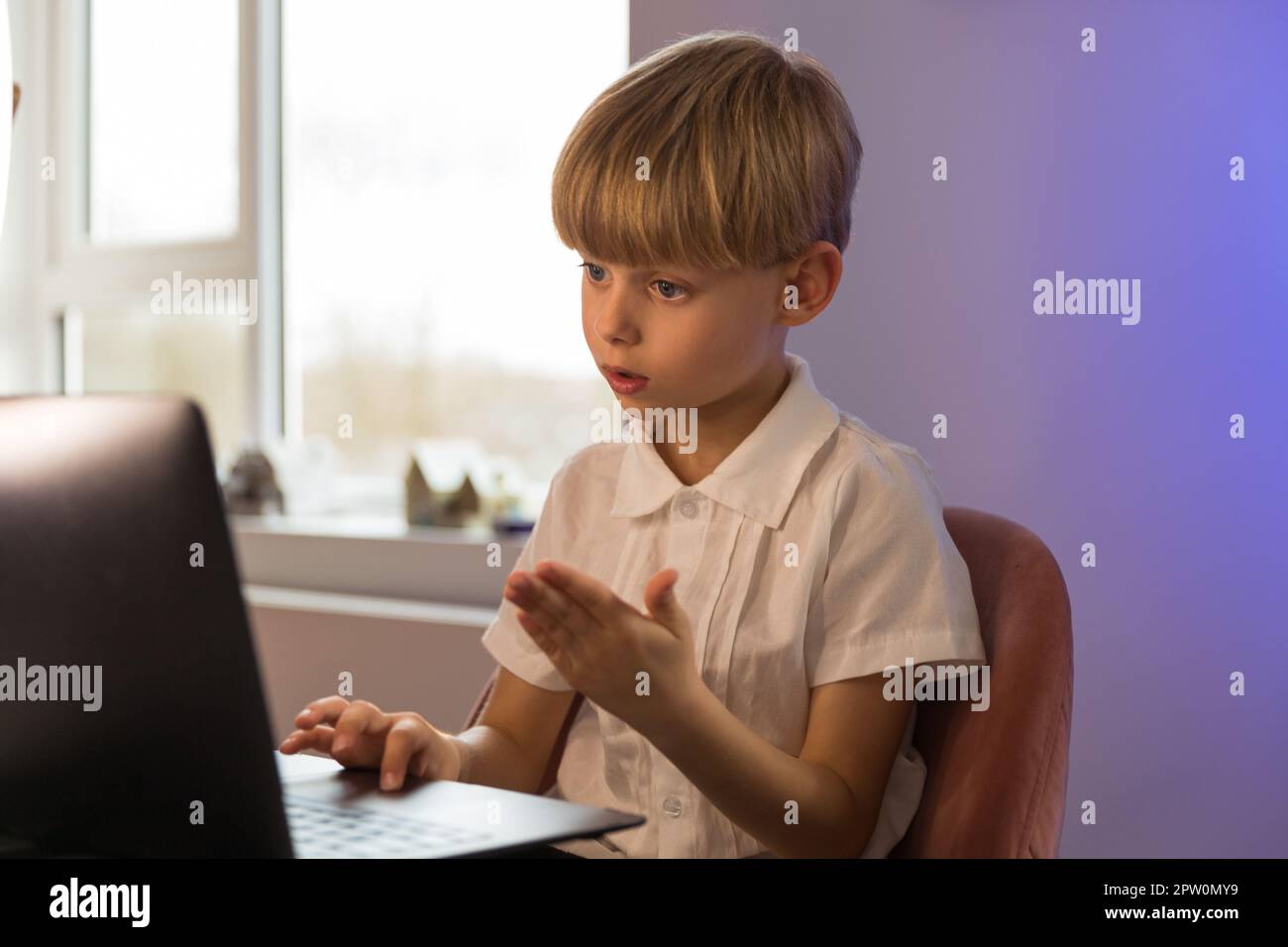 cheerful Caucasian boy uses laptop to make video call with his teacher ...