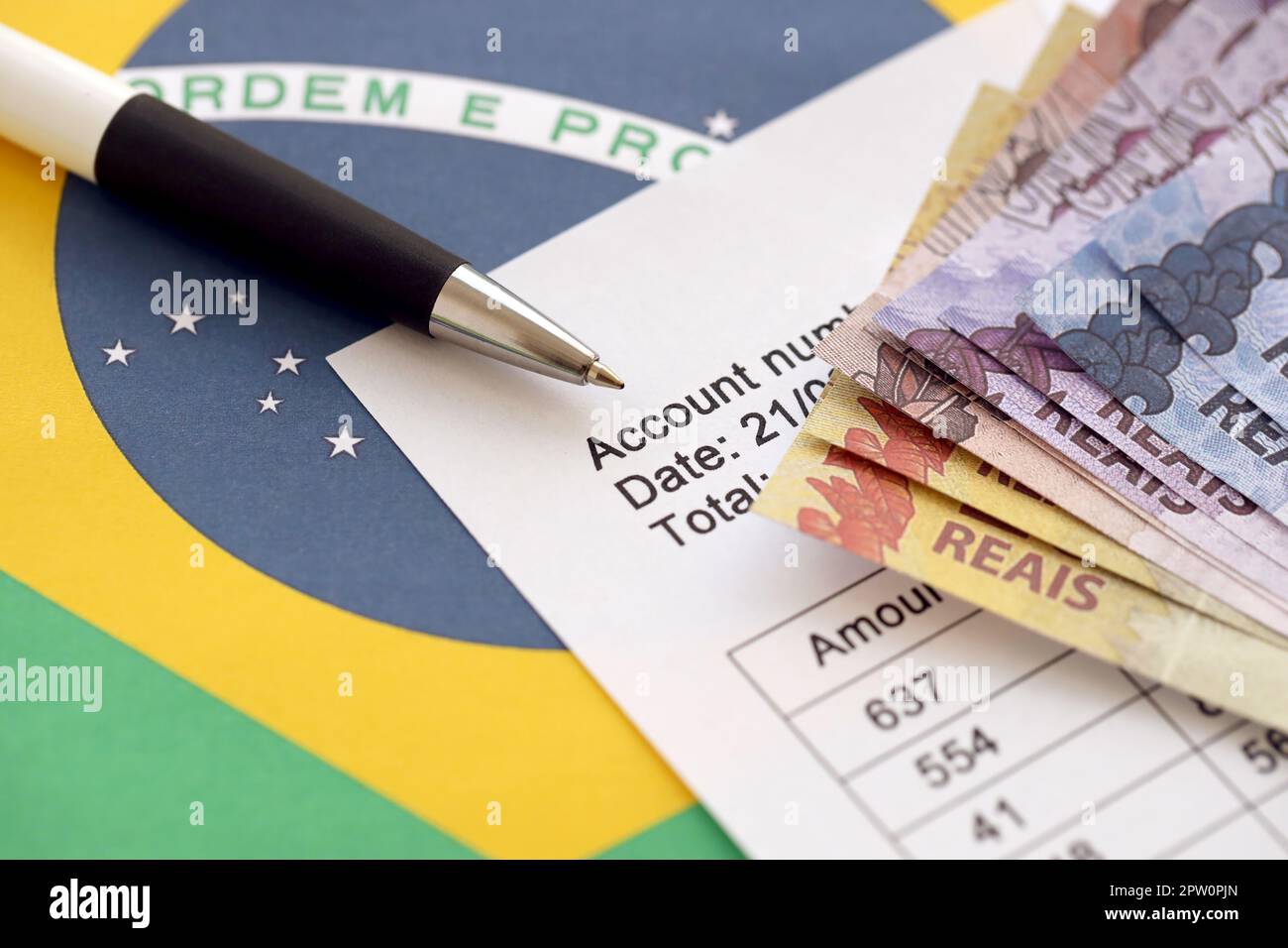 Pen with Brazilian money bills on flag of Brazil republic. Concept of ...