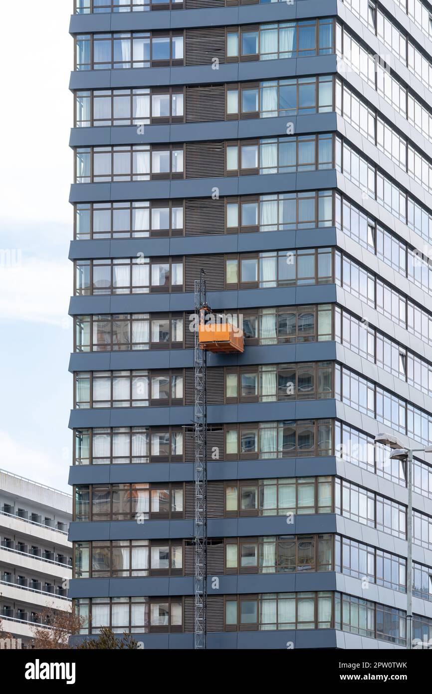 Maintenance workers on a hanging cradle or lifting platform carrying ...