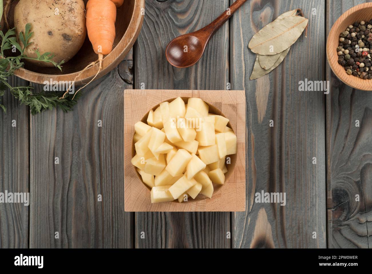 Bowl full of cut into cubes raw yellow potato on kitchen wooden table ...