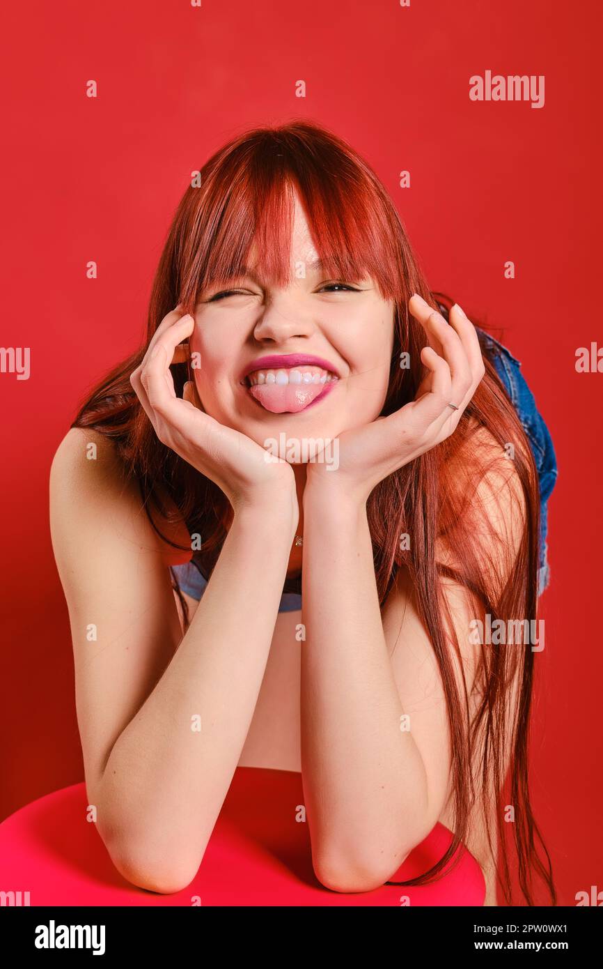 Funny Teenager Girl With Red Hair Sticks Out Tongue Props Chin With