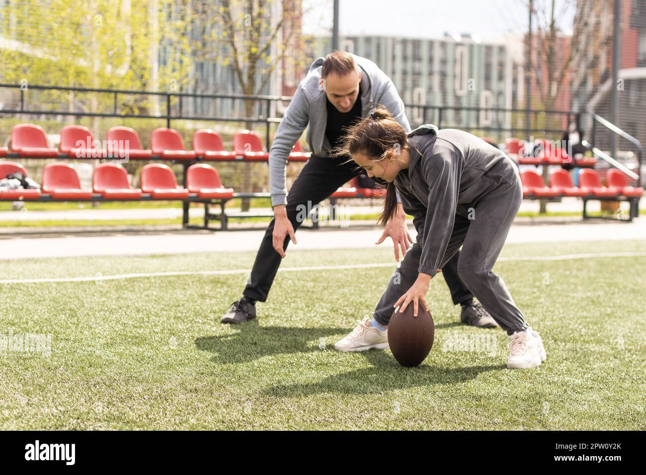girl holding an oval brown leather rugby ball and smiling while playing ...