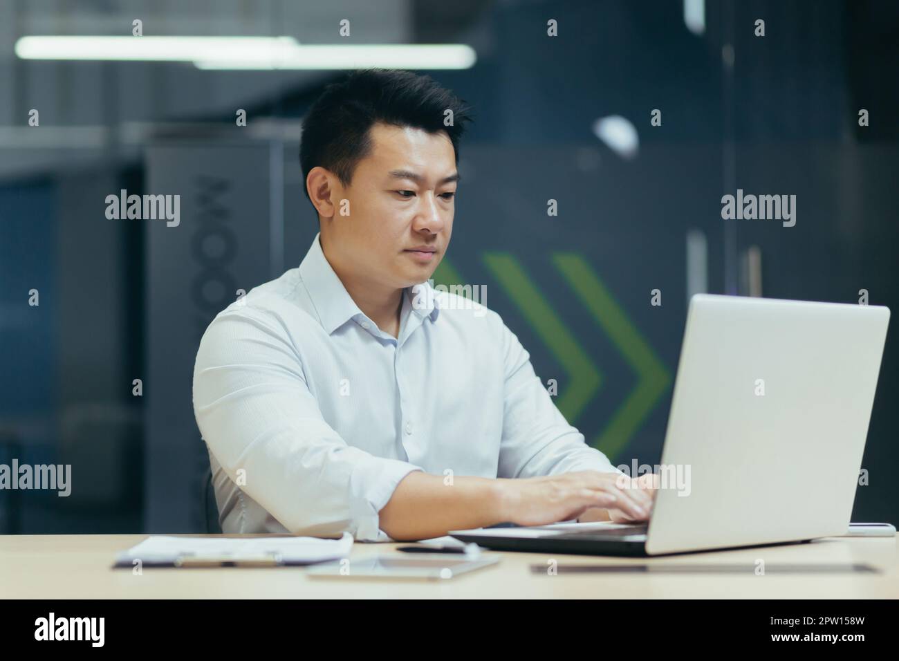 A young man of Asian origin programmer, developer works in the office ...