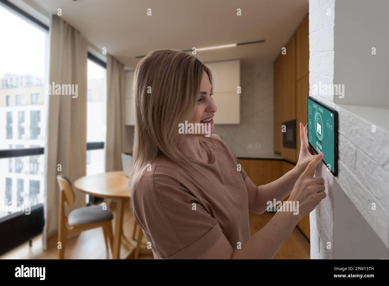 pretty blonde woman using smart home control panel Stock Photo - Alamy