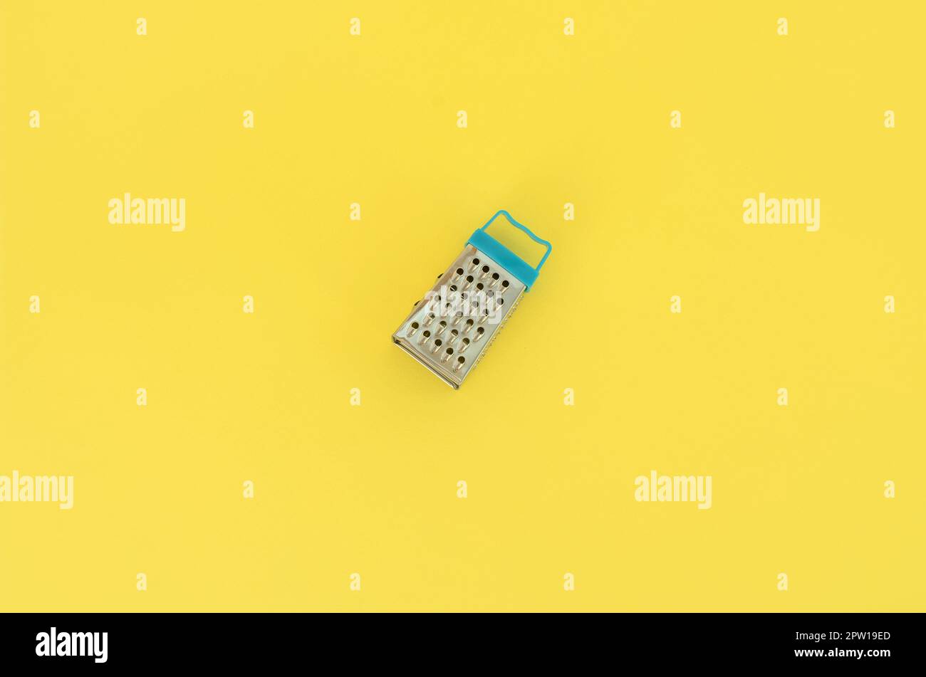 Stainless steel grater lies on a pastel colored paper. Kitchen ...