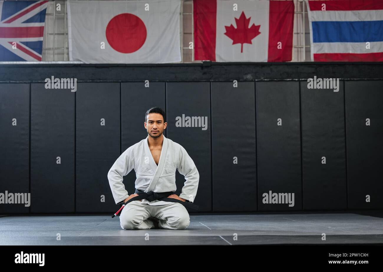.Martial arts, black belt and sitting fighter inside dojo for training. Defence club, champion ...