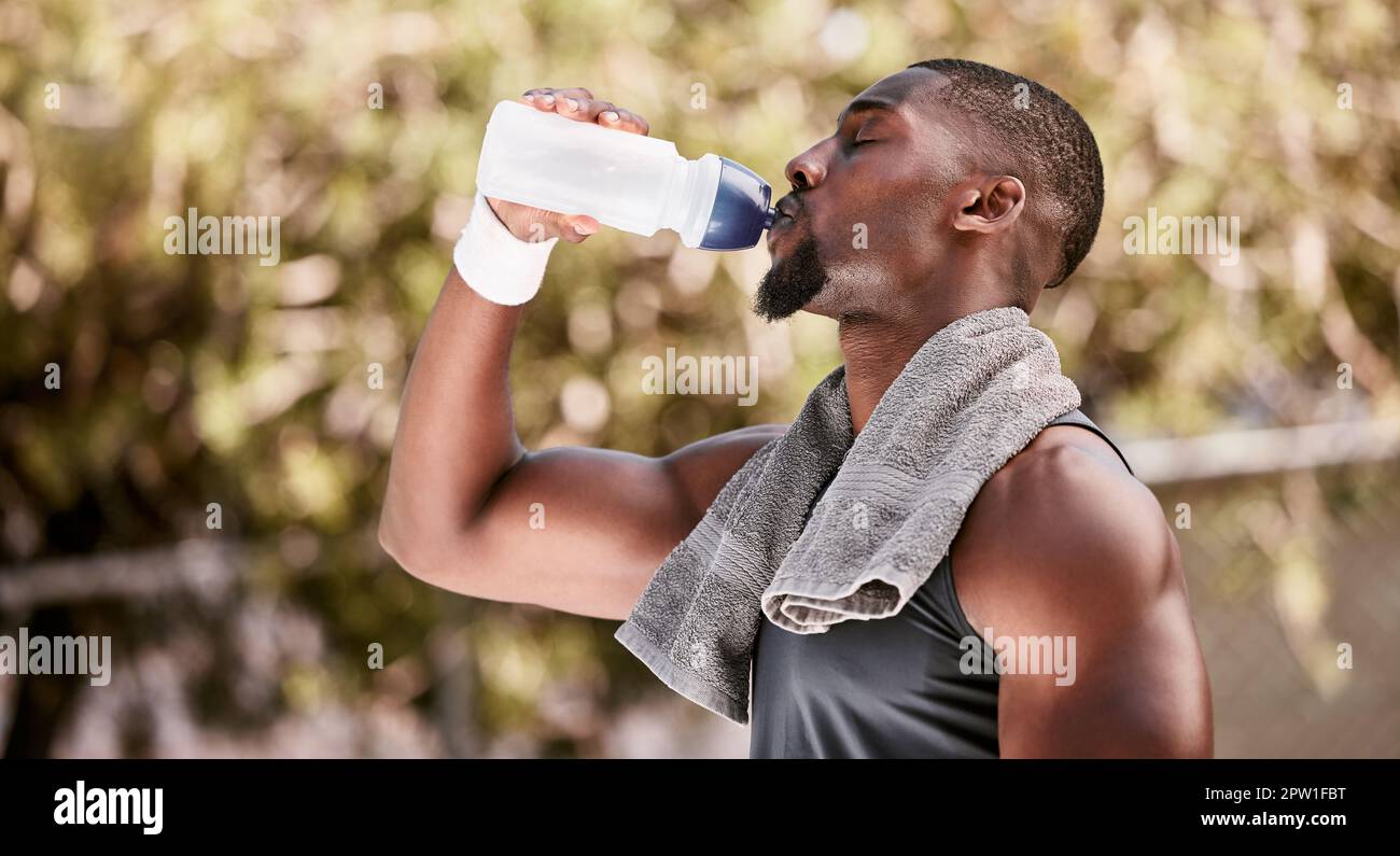Athlete drinking water from a bottle during an outdoor workout. Fit ...