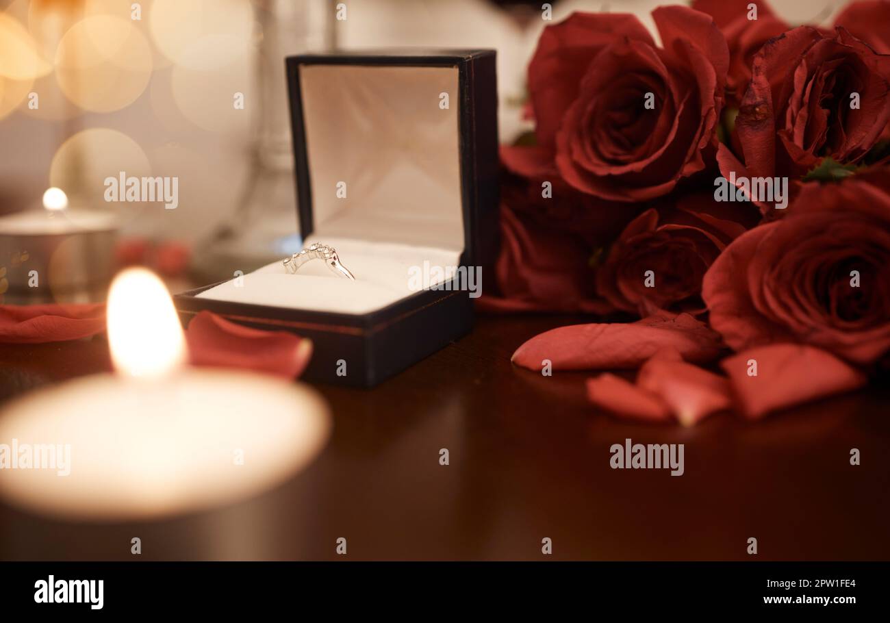 Closeup of romantic engagement ring box, fresh red roses and candles in ...