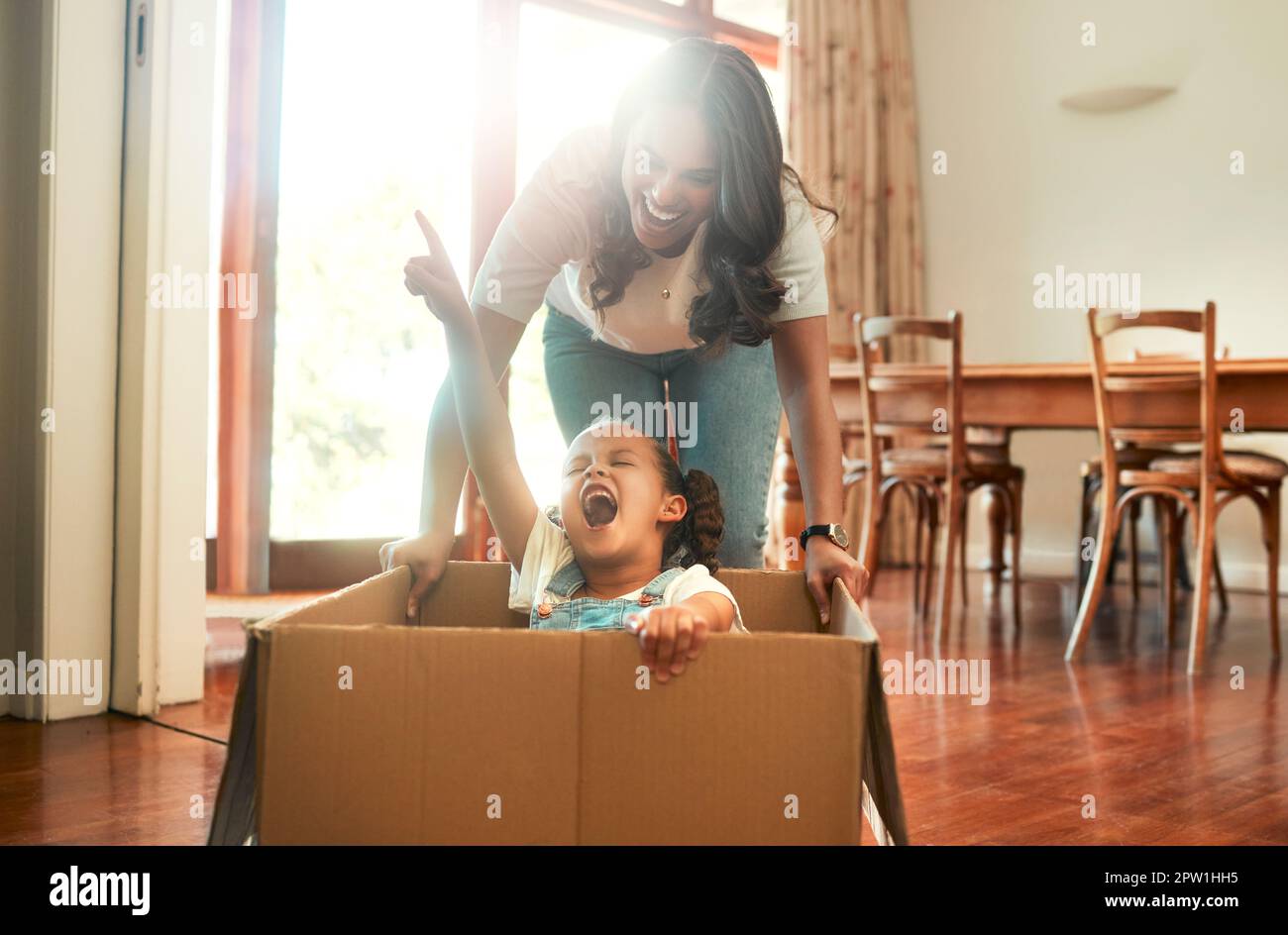 Mother and daughter playing with a cardboard box. Excited little girl ...