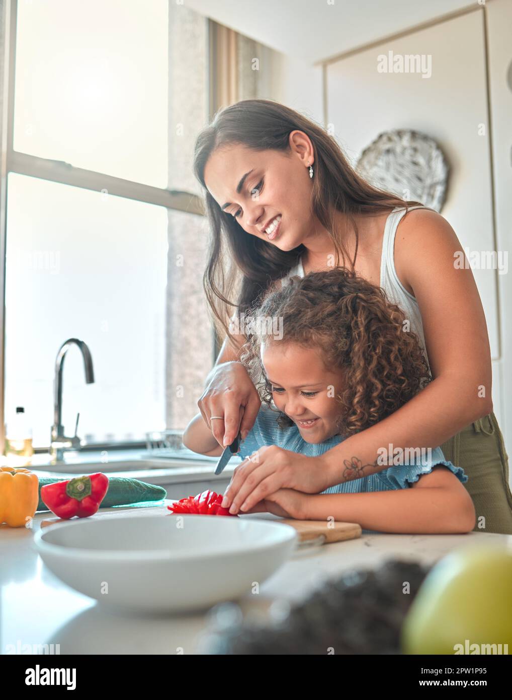 Loving mother and small daughter chopping a red pepper and making a ...
