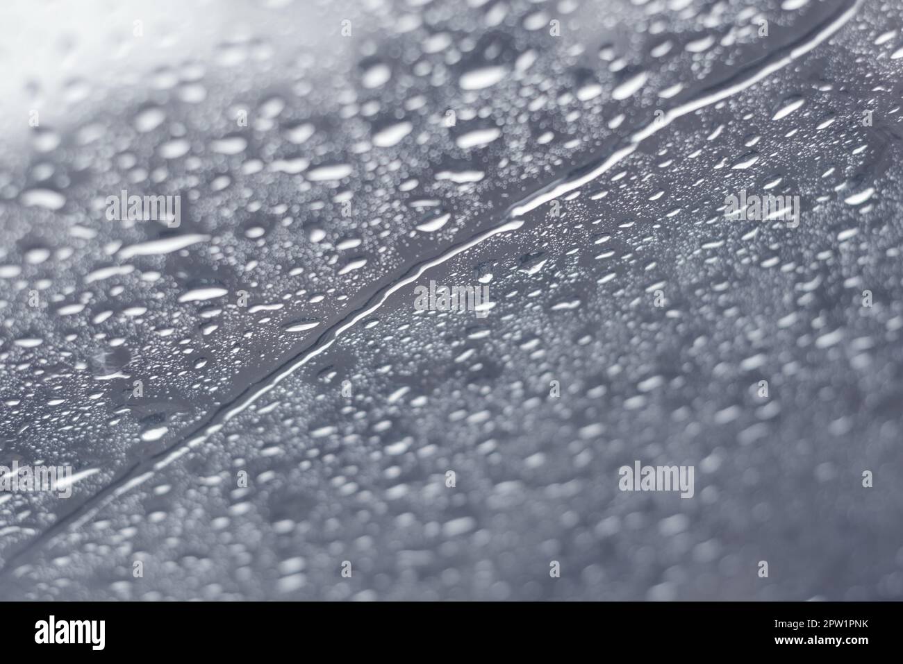 Raindrops dripping across a window in a cold winter day. Close up ...
