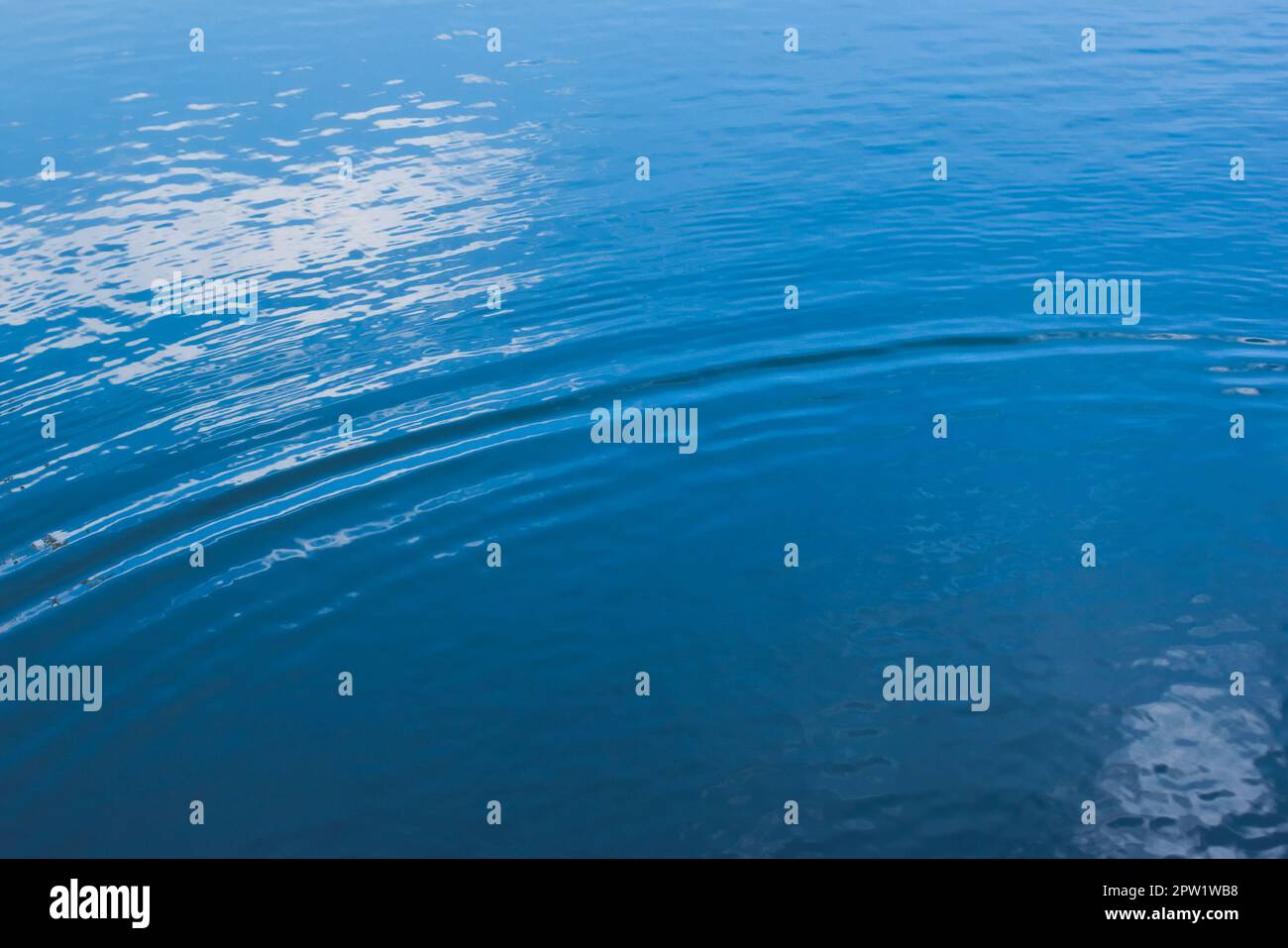 Small ripples on calm water with deep blue reflections Stock Photo - Alamy