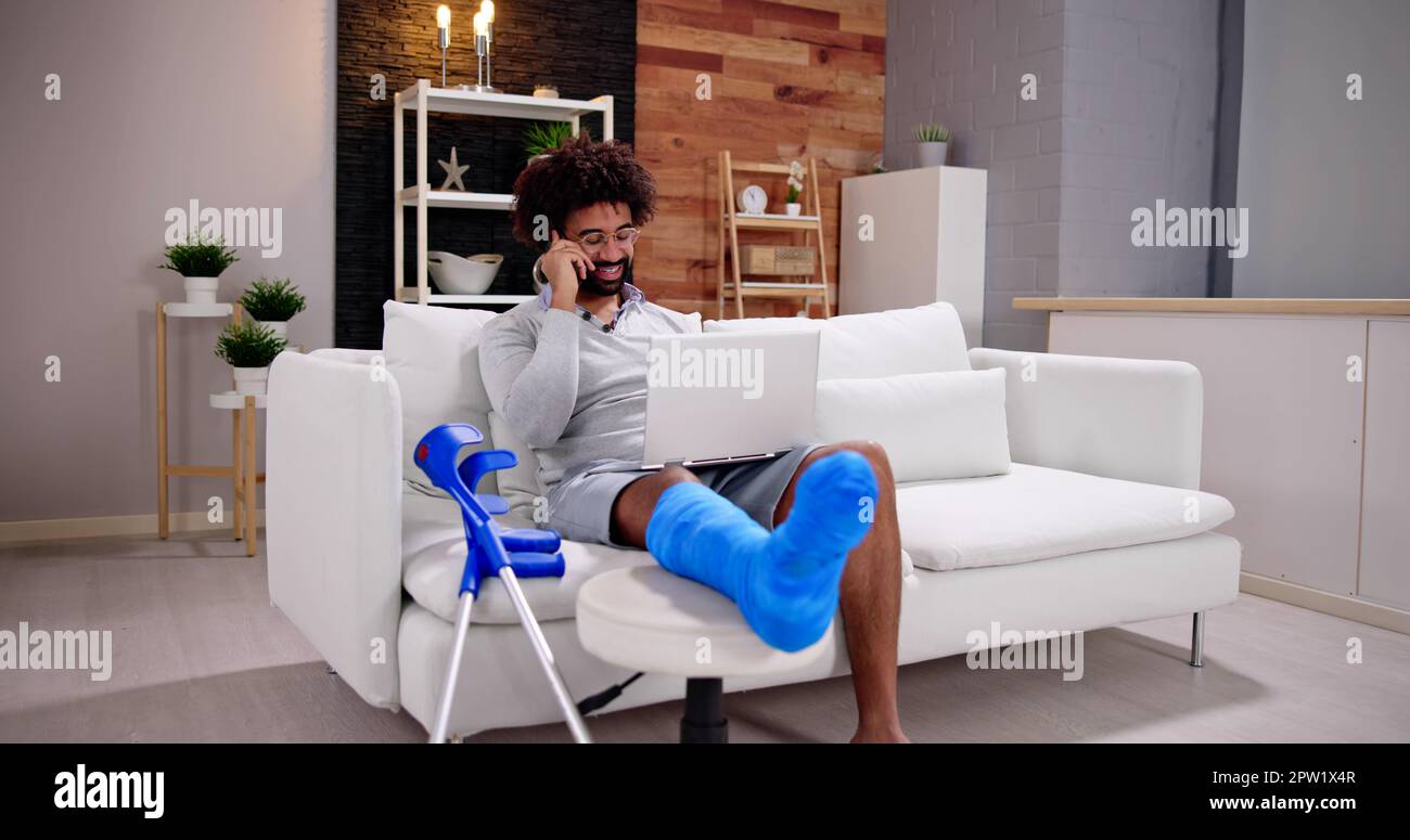 Happy Young Man With Broken Leg Sitting On Sofa Talking On Mobile Phone ...