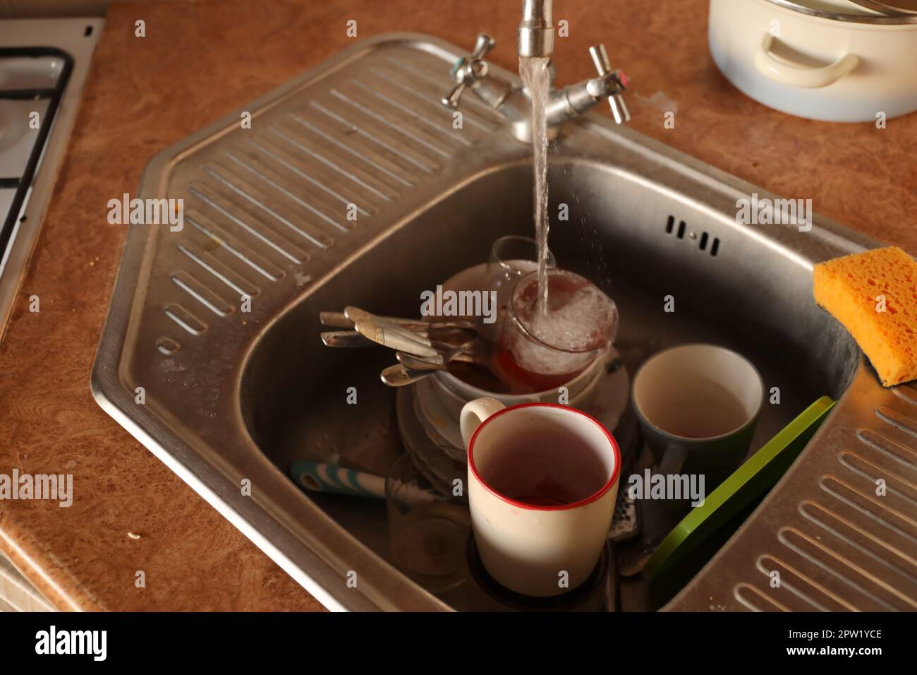 Stack of dirty dishes with food leftovers in the kitchen sink. Unwashed ...