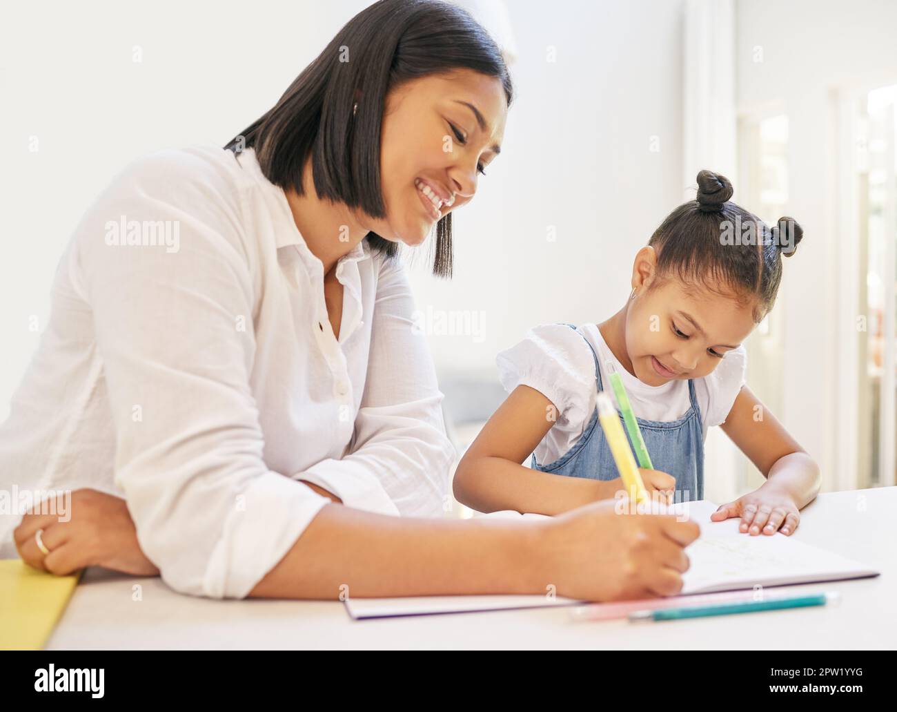 Mixed race mother helping her daughter with her homework. Mom teaching ...