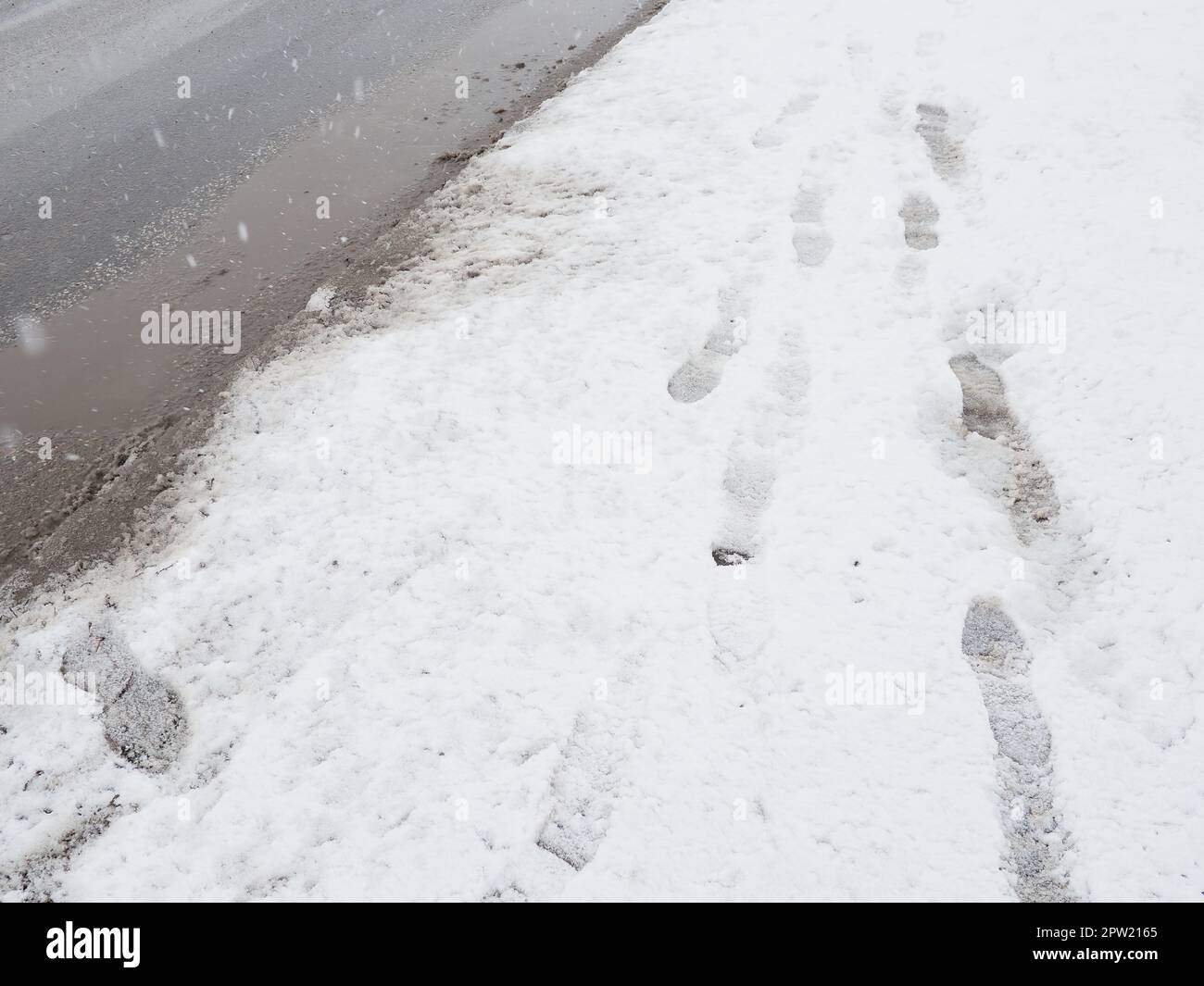 Roadside with a snowdrift. Difficult driving conditions. Wet slippery ...