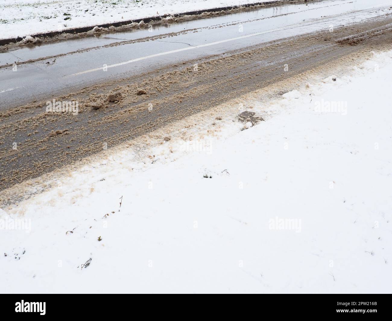 Roadside with a snowdrift. Difficult driving conditions. Wet slippery ...