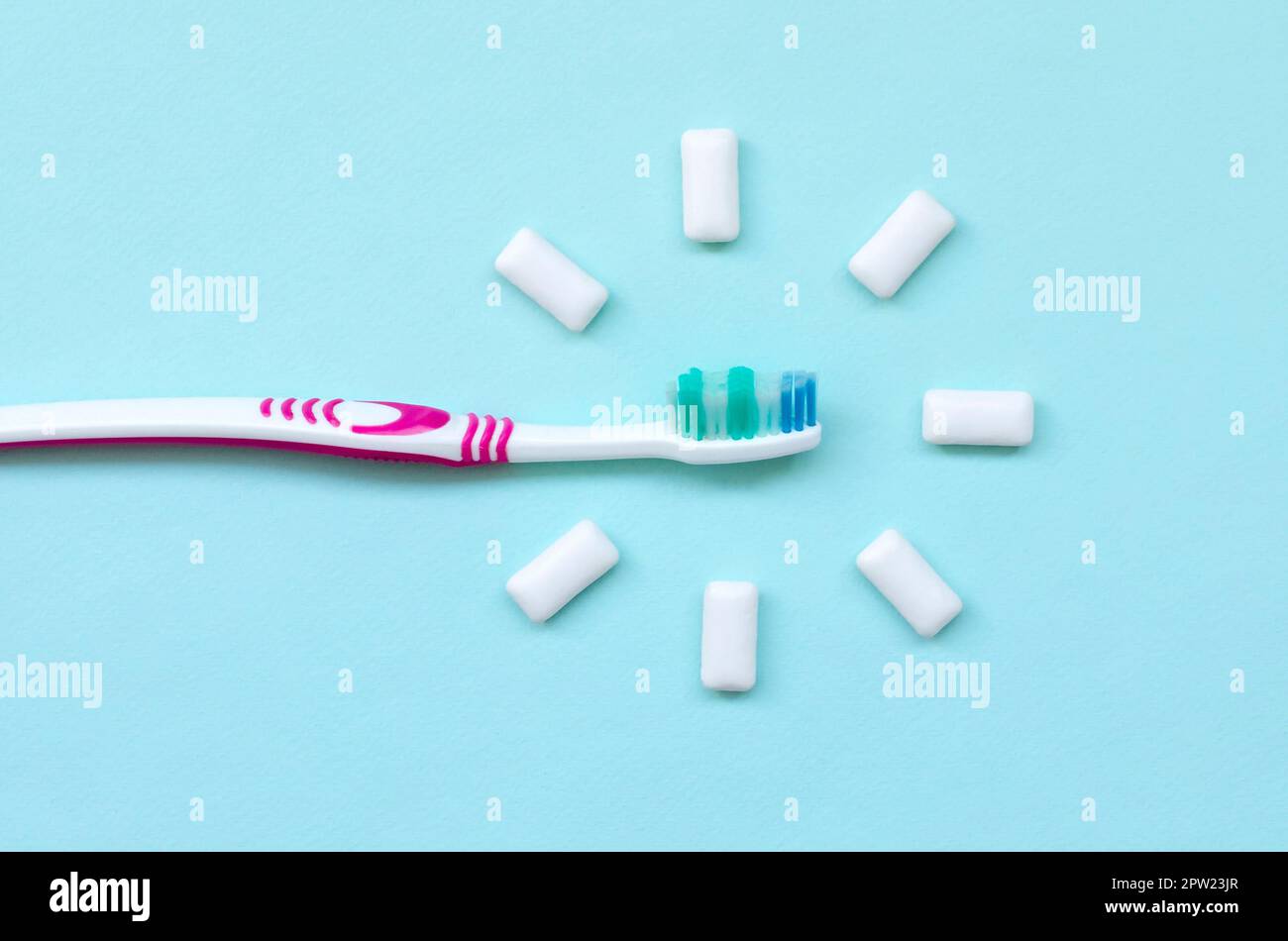 Toothbrush and chewing gums lie on a pastel blue background. Top view ...