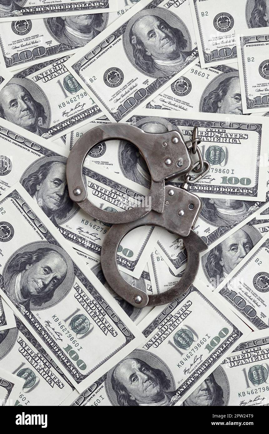 Police handcuffs lie on a lot of dollar bills. The concept of illegal ...