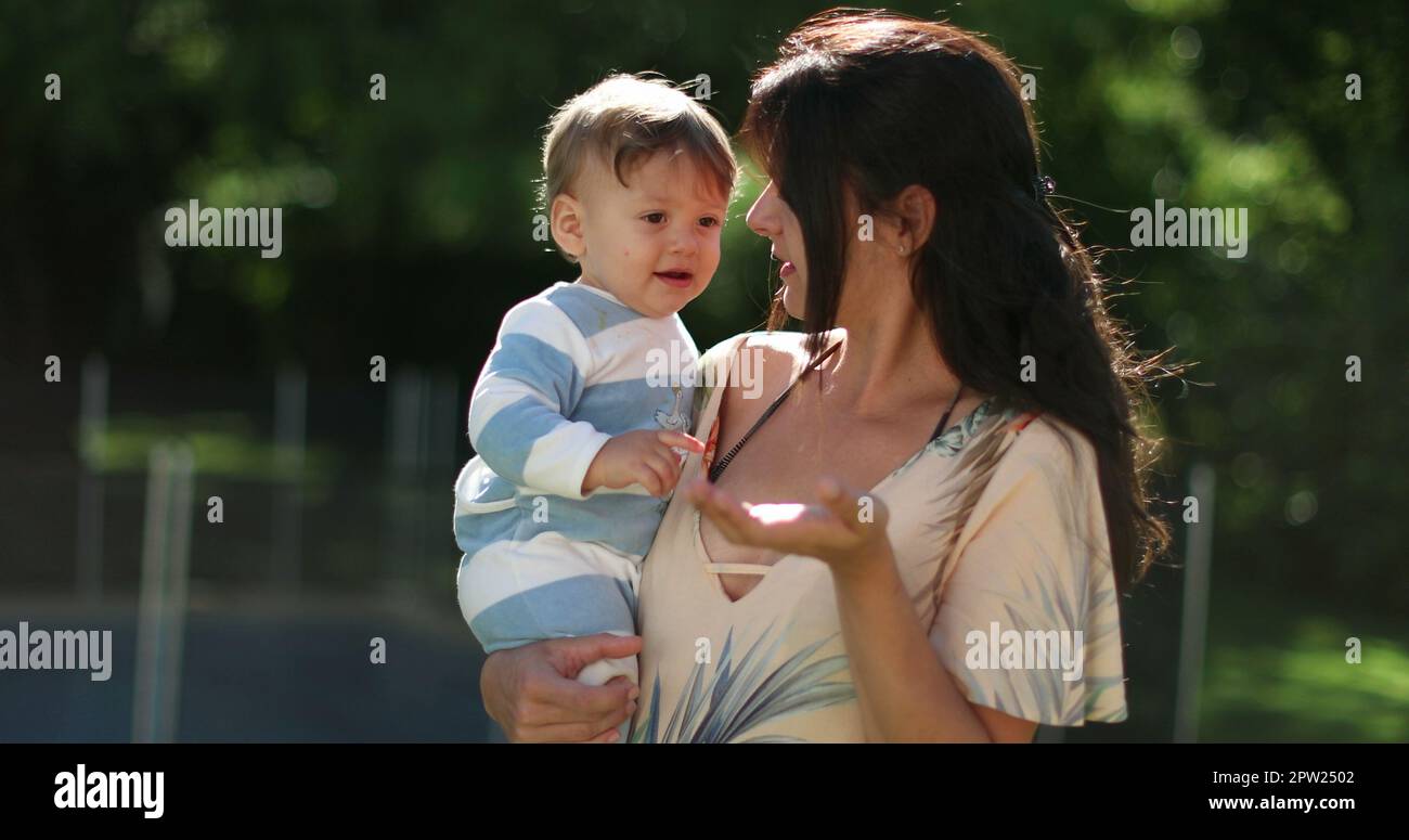 Candid mom holding baby son in arms outside in nature Stock Photo - Alamy