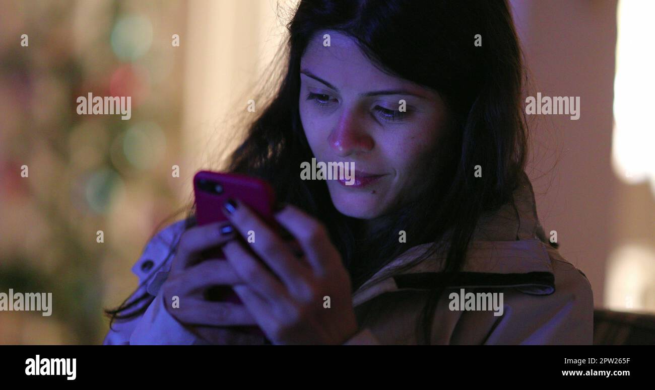 Candid woman looking at cellphone screen at night. Real life person ...