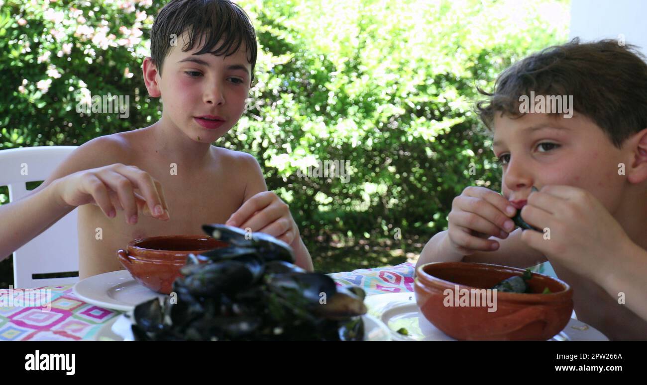 Casual kids eating seafood mussels for lunch during summer day Stock ...