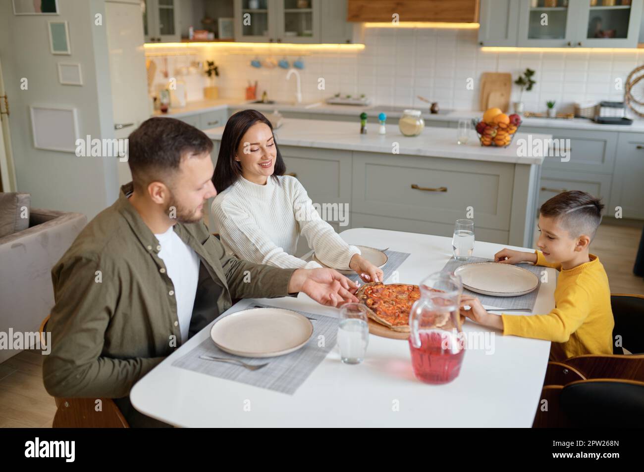 Happy mother, father and son eating italian homemade pizza cooked ...