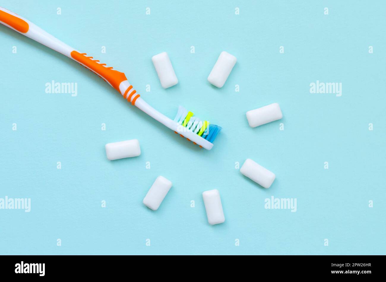 Toothbrush and chewing gums lie on a pastel blue background. Top view ...