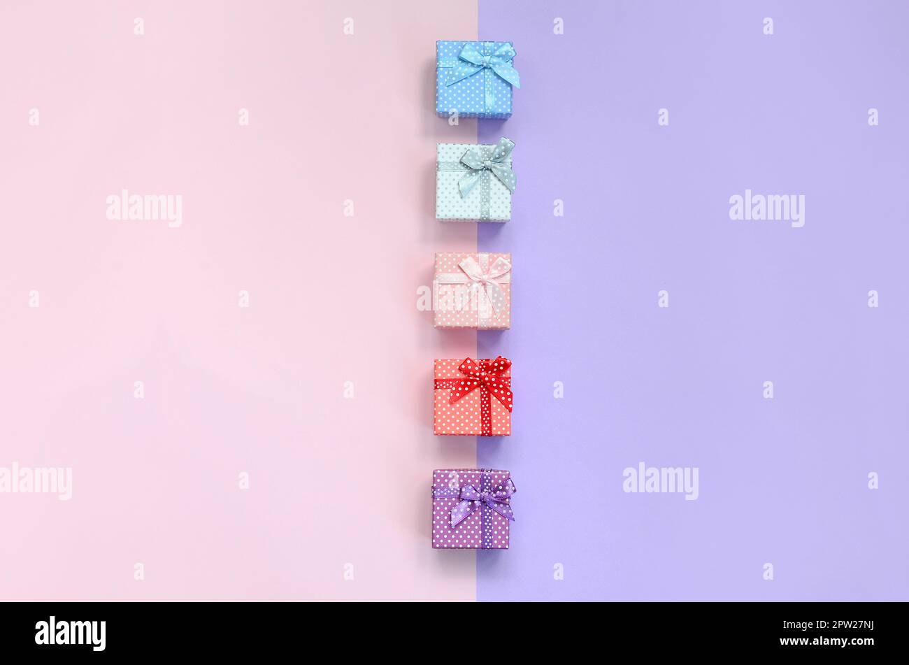 Small gift boxes of different colors with ribbons lies on a violet and ...